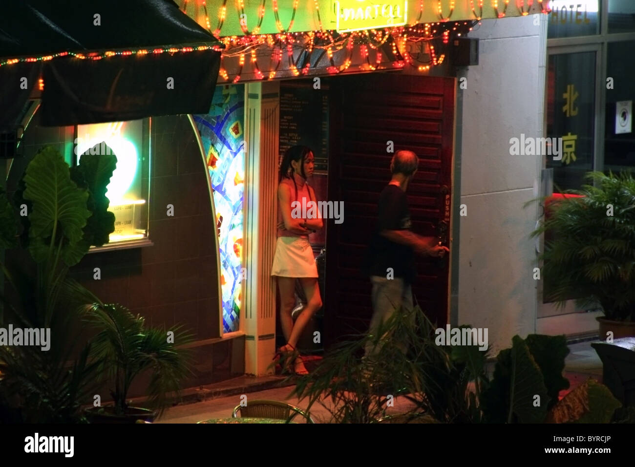 A woman bar hostess is watching a male customer leave a colorful ...