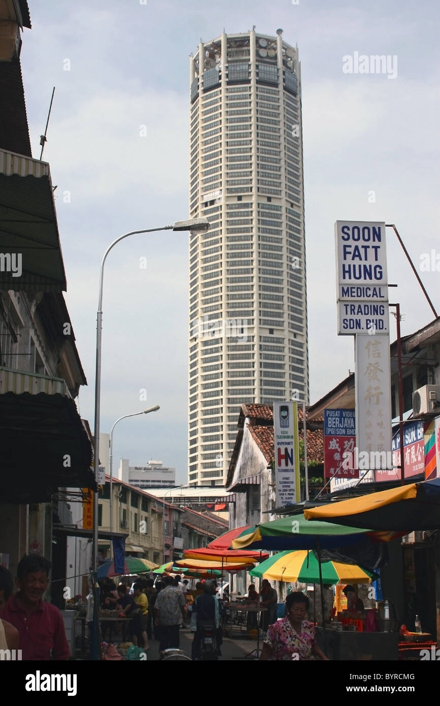 The KOMTAR Tower rises over a busy shopping district filled with people ...