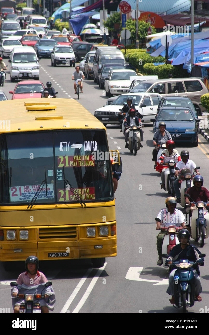 A big yellow city bus is weaving through heavy traffic on a busy street ...