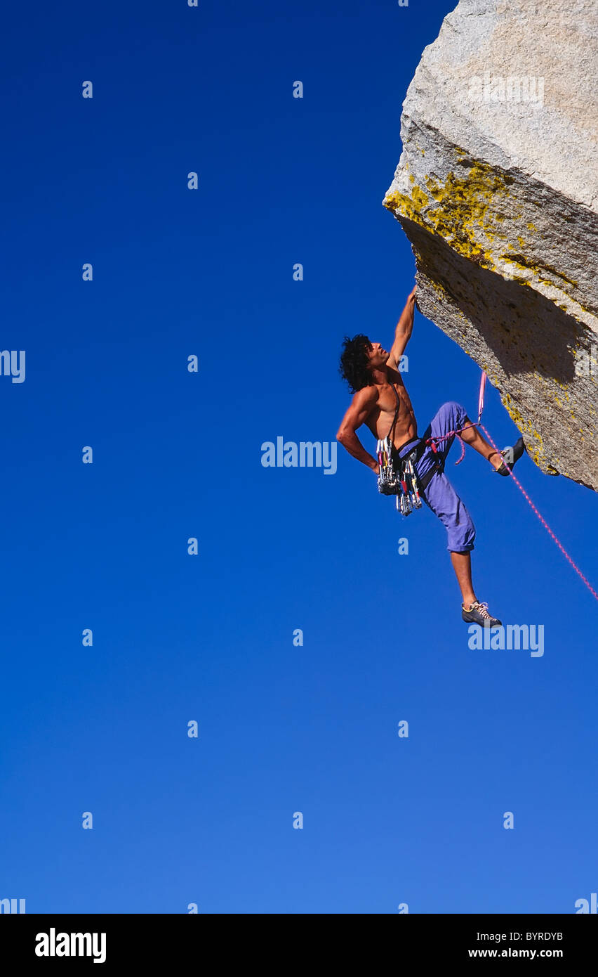 Rock climber struggles for his next grip on a overhanging cliff Stock ...