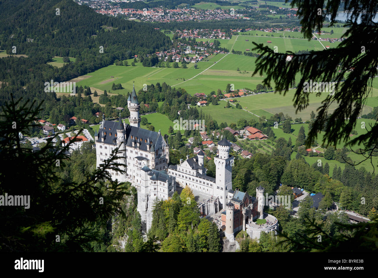 bavarian castle on a mountain side with fields and a village in the ...