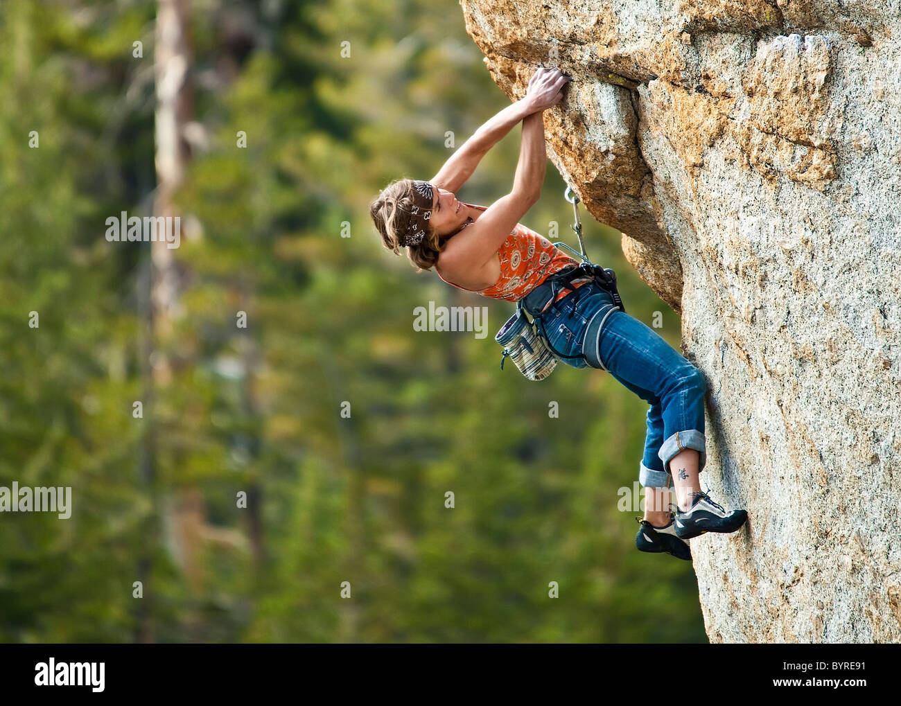 Female climber clinging to an overhanging rock face Stock Photo - Alamy