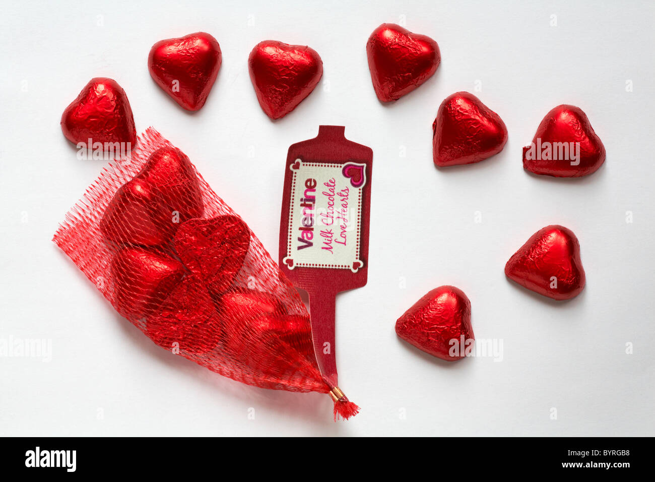 Valentine milk chocolate love hearts in red foil spilling out of netted ...