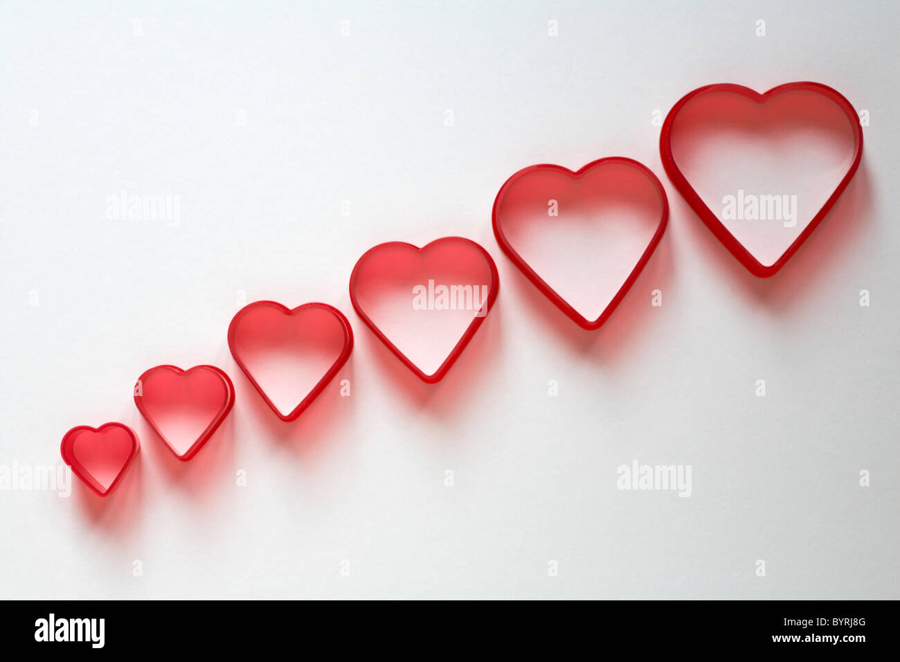 Row of red heart shaped cutters increasing in size isolated against ...