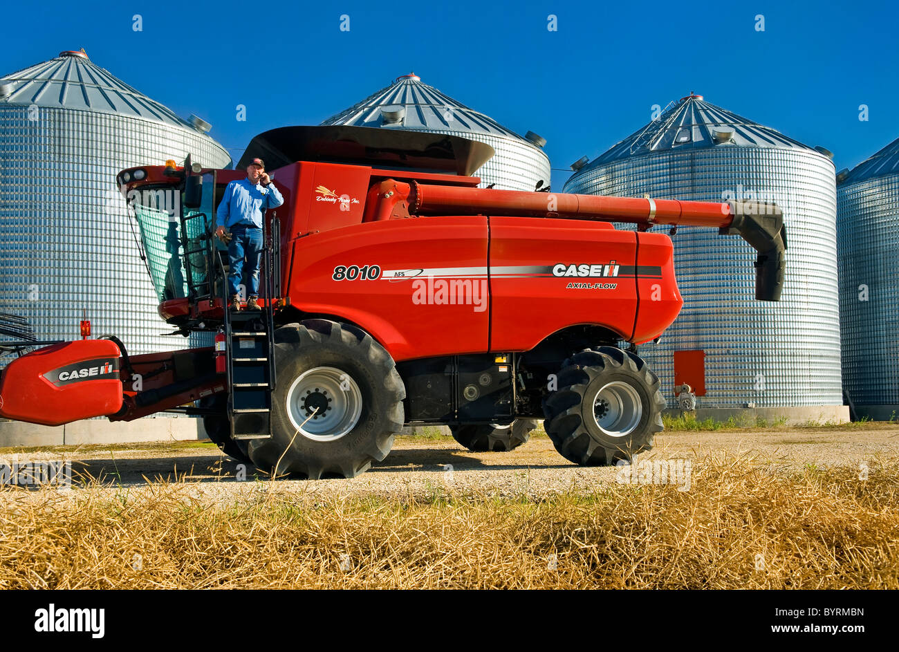 A farmer talks on his cell phone while looking out over his field of ...