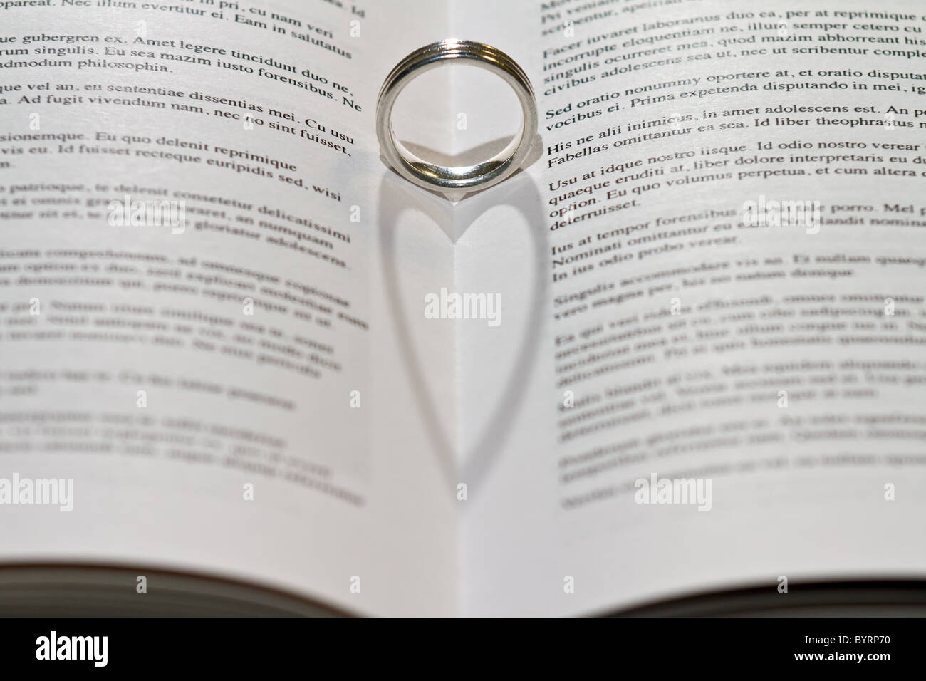 Ring casting heart shadow in book Stock Photo - Alamy