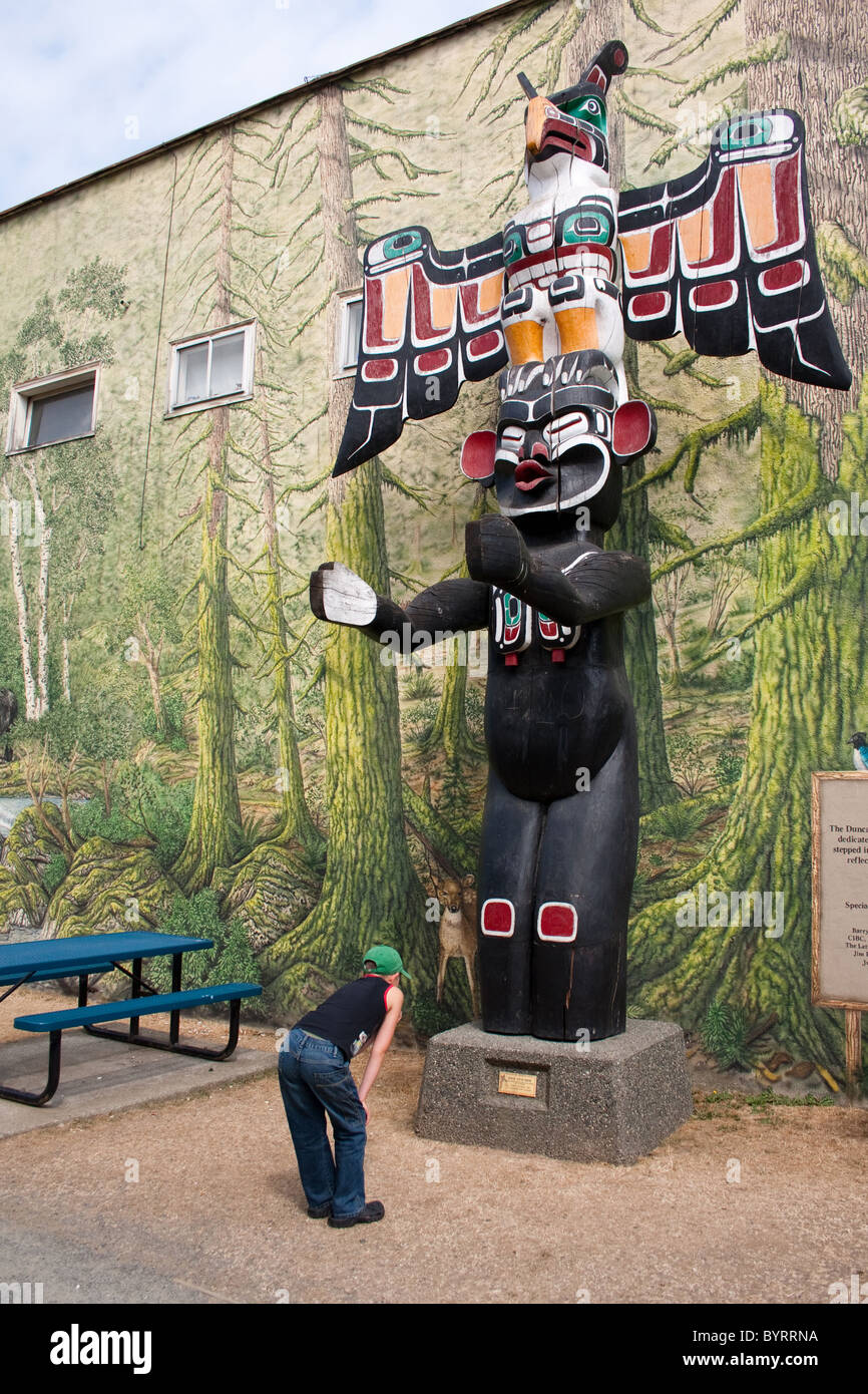 A boy reading the plaque on a totem pole in Duncan, BC, Canada. Duncan ...