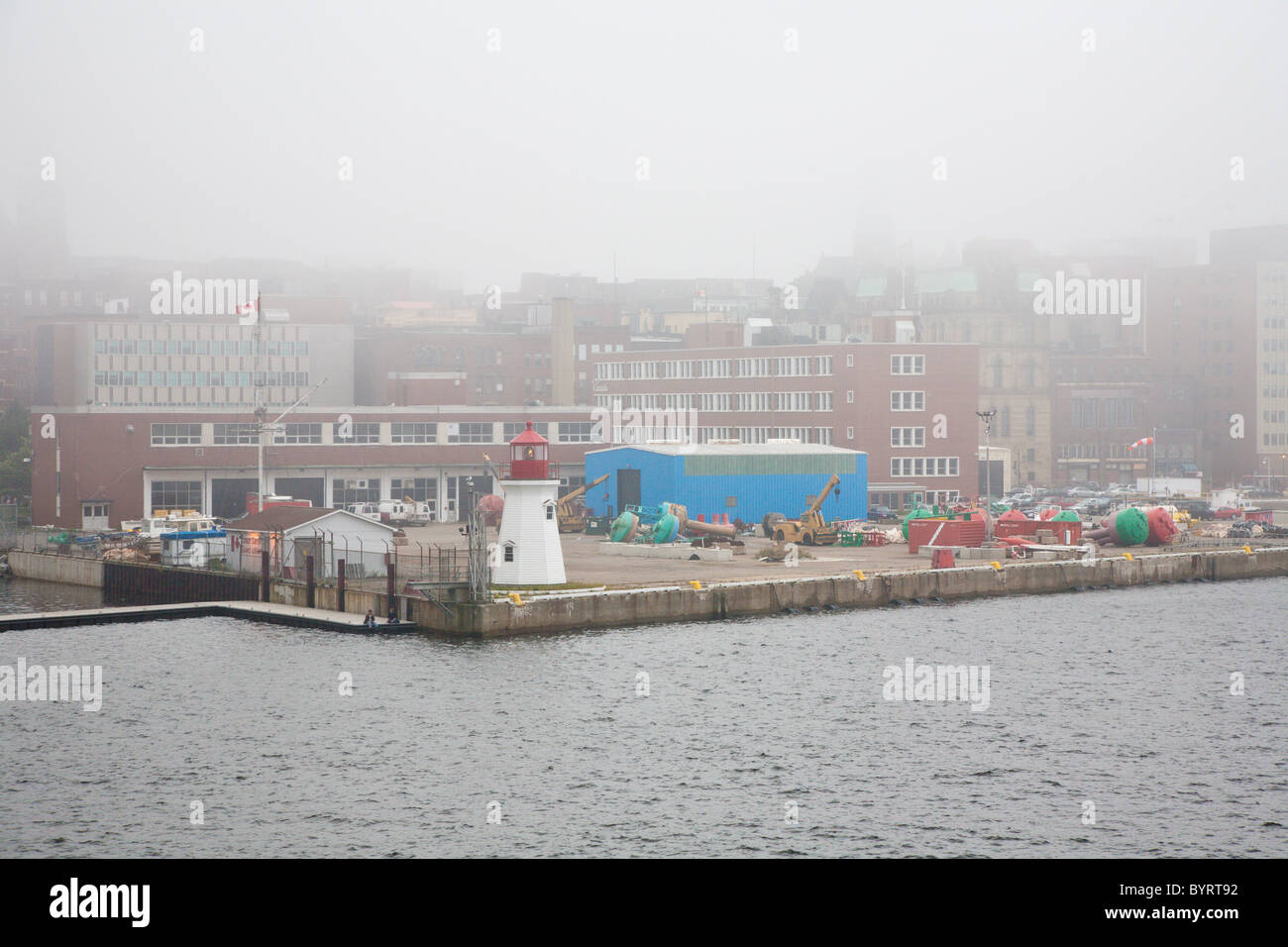 Lighthouse on corner of commercial dock on a foggy day at port in ...