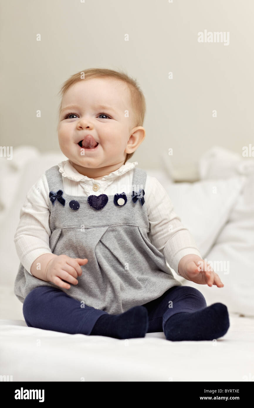 portrait of hungry 6 months female child sitting on bed. Vertical shape ...