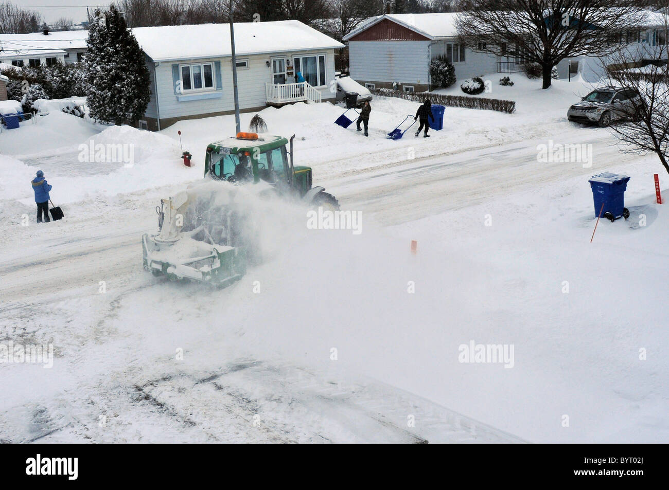 Residents in a street in Quebec, Canada shovel snow from their yards ...