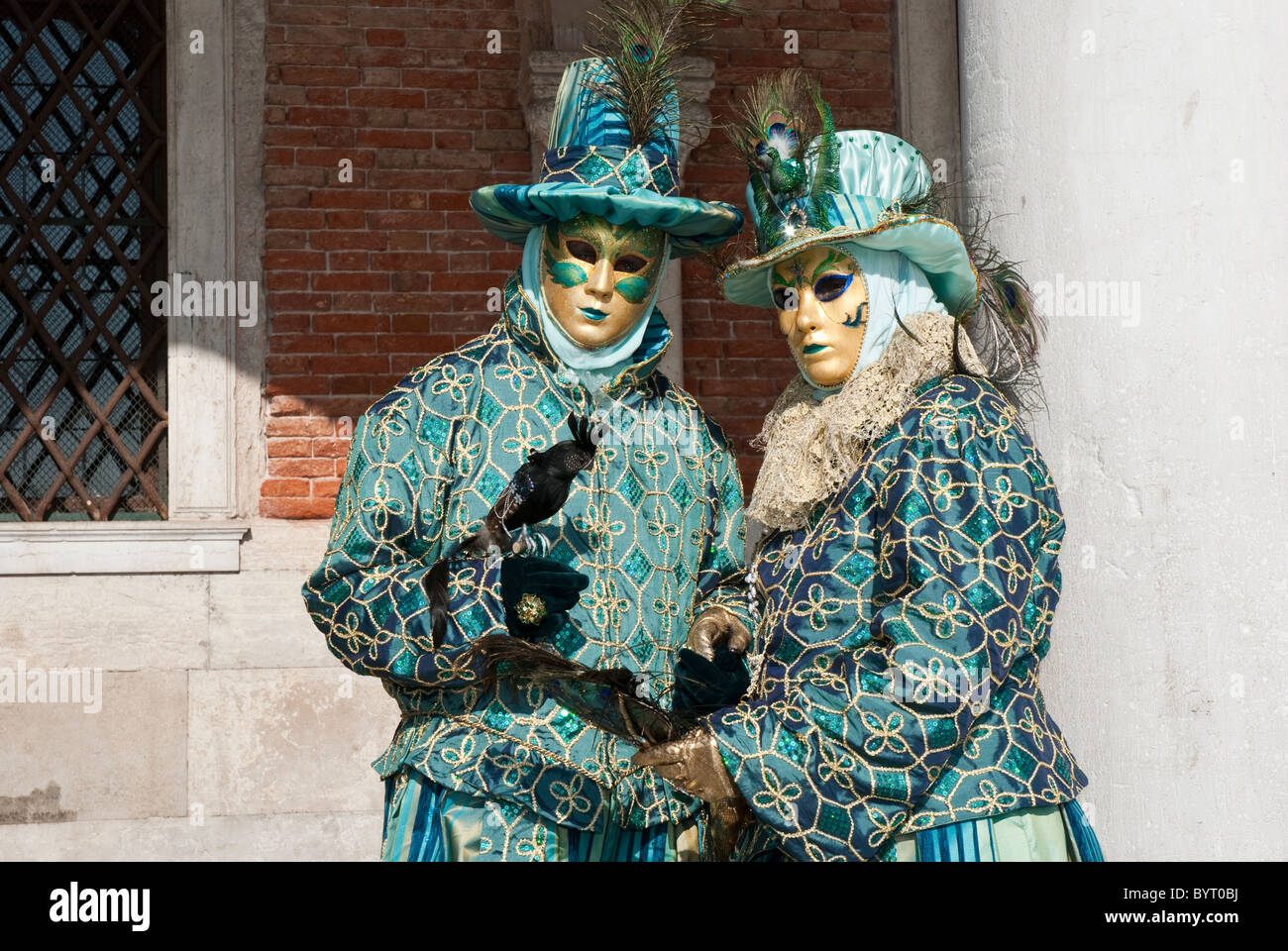 A couple of venetian masks during Carnival handling bird and peacock ...