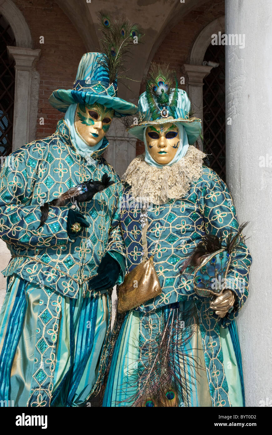 A couple of venetian masks during Carnival handling bird and peacock ...