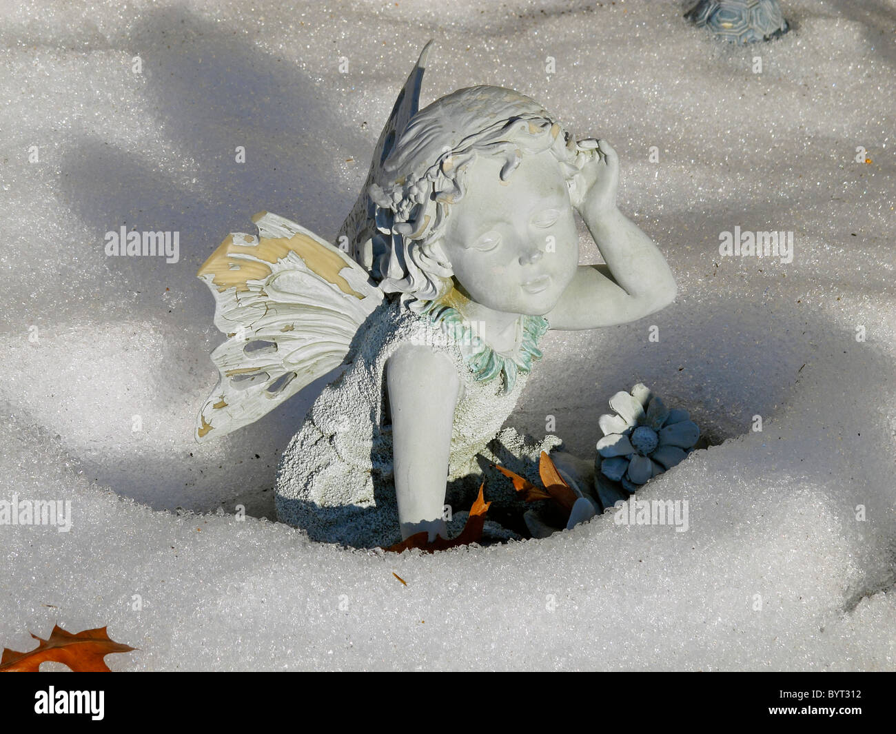 A garden statue of an angel appearing through the melting snow Stock ...