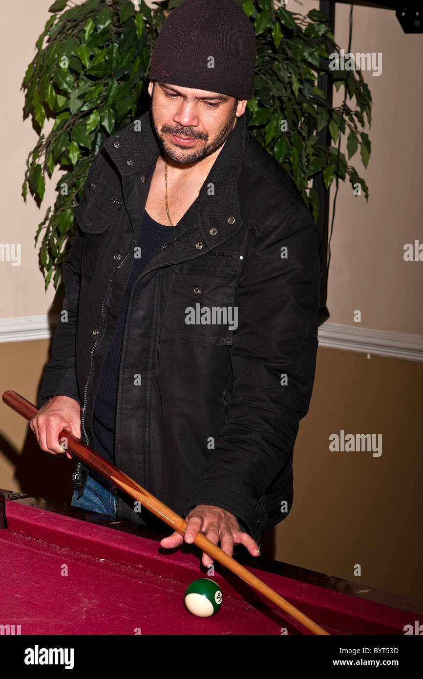 Latino guy playing pool table Stock Photo - Alamy