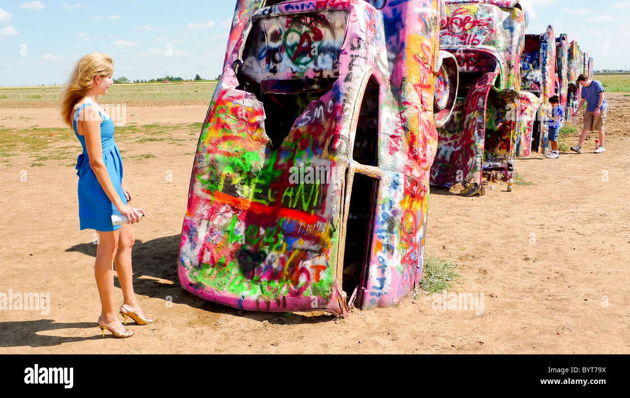 Woman in blue dress contemplates spray painting Cadillac at Cadillac ...
