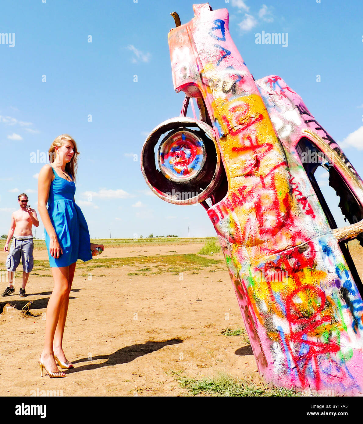Woman in blue dress contemplates spray painting Cadillac at Cadillac ...