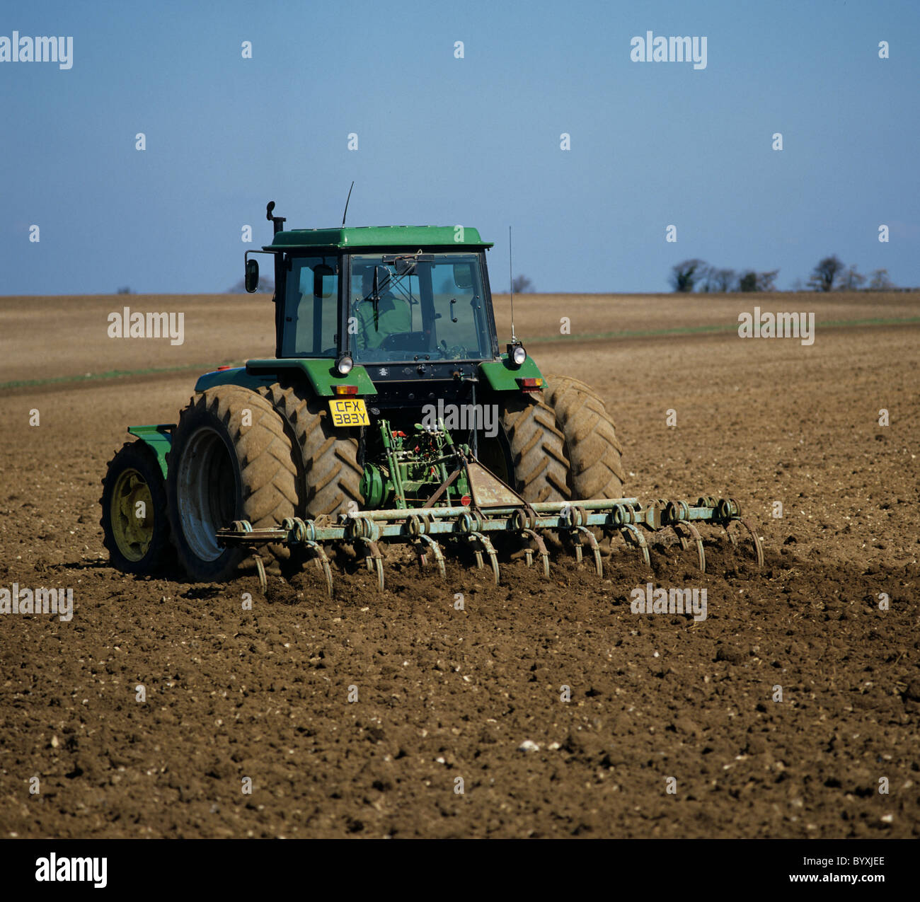 John Deere tractor and sprung tyne cultivator harrowing ploughed field ...