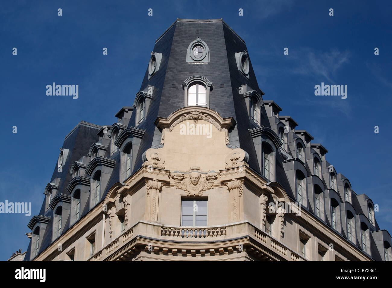 low angle of a french style building facade and roof line with a blue ...
