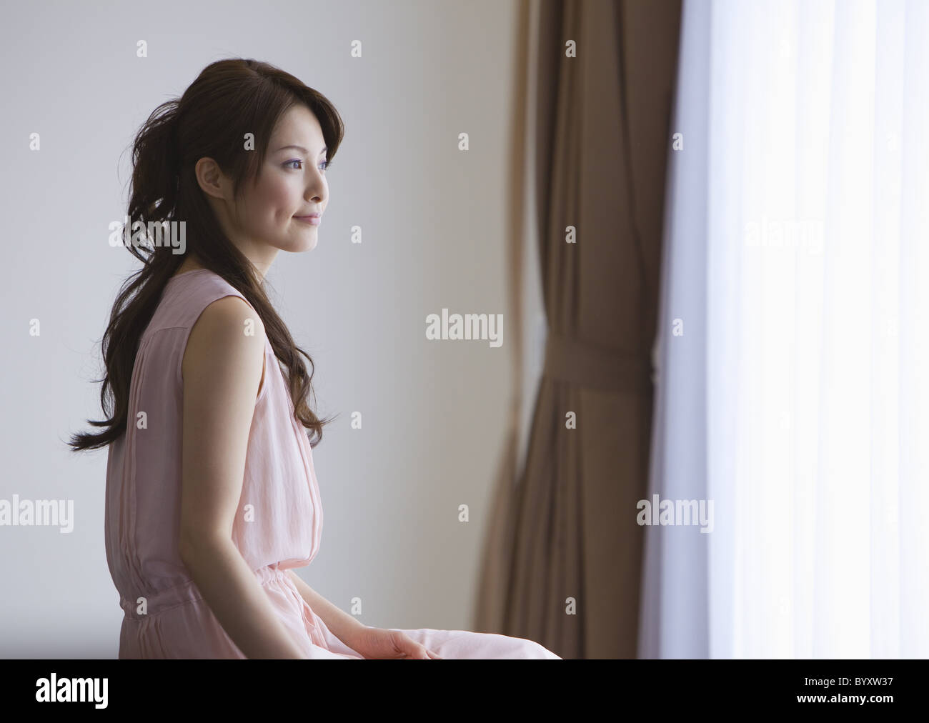 Woman sitting near window Stock Photo - Alamy