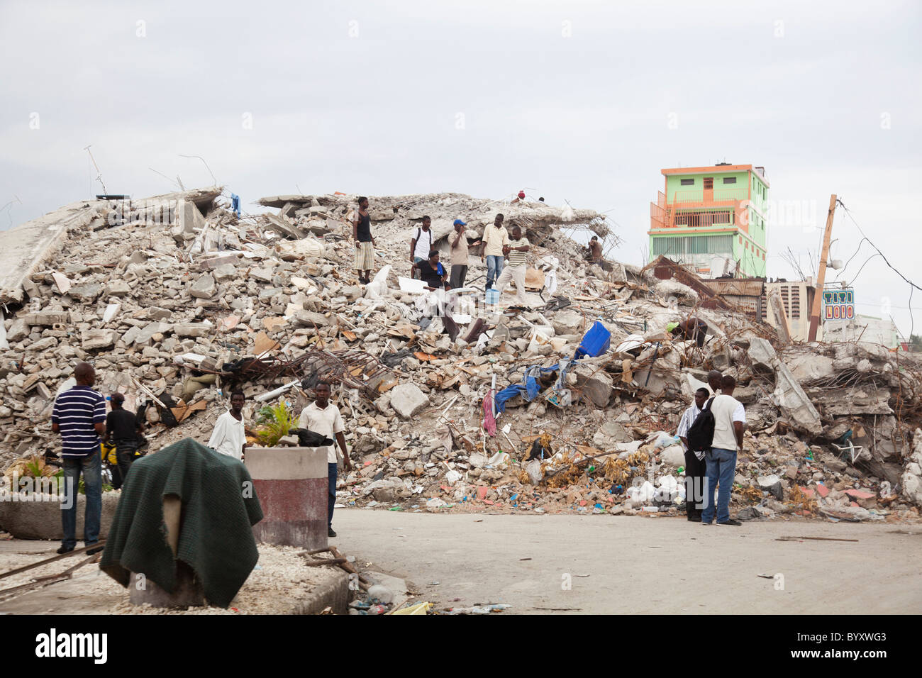 haitian people standing amongst the ruins of collapsed buildings after ...