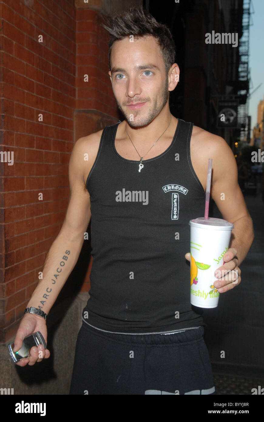 Jason Preston walking in SoHo with a fruit juice. He has his right arm ...