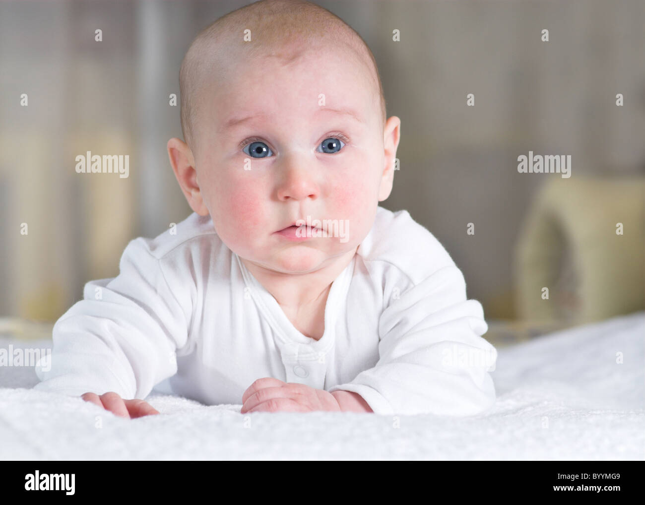 Serious baby is lying down on her stomach Stock Photo - Alamy