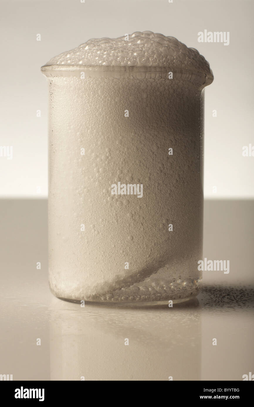 effervescent table dropped in a laboratory beaker full with water ...