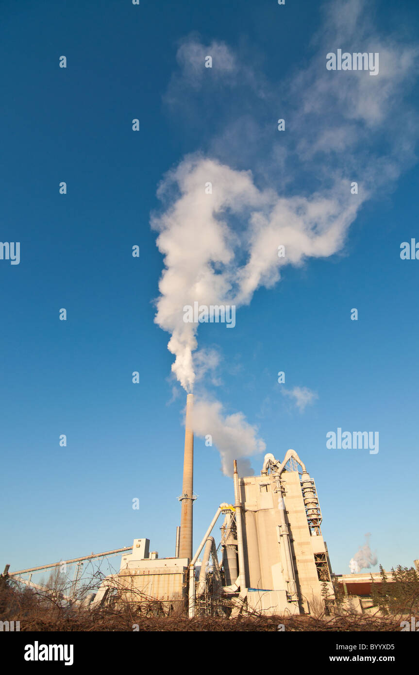 A manufacturing facility pumps smoke into the air from two smokestacks ...
