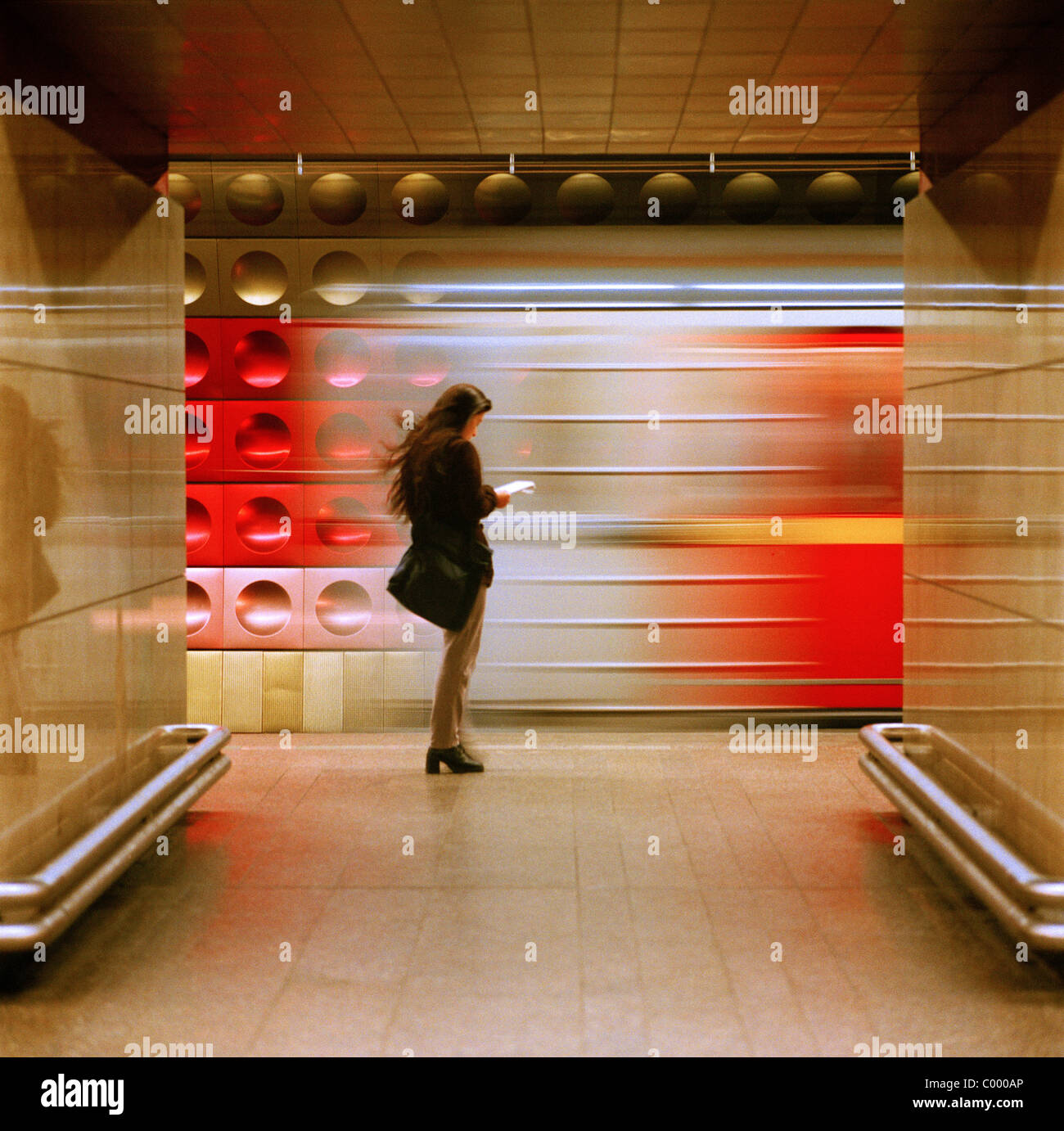Girl reading the paper as a tube train arrives Stock Photo - Alamy