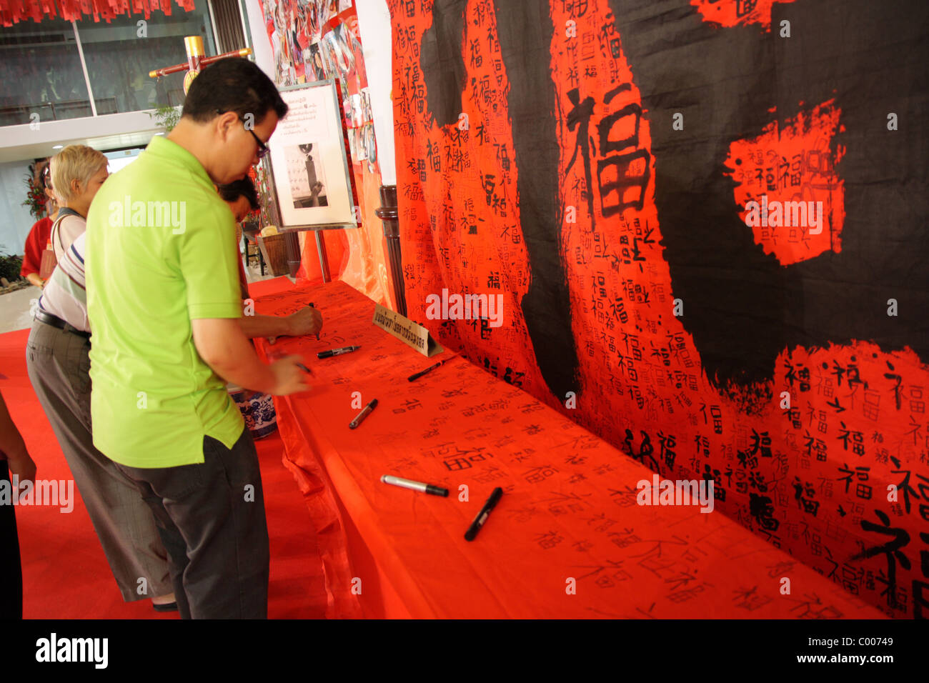 People writing Chinese Lucky Word on red fabric , Chinese new year ...