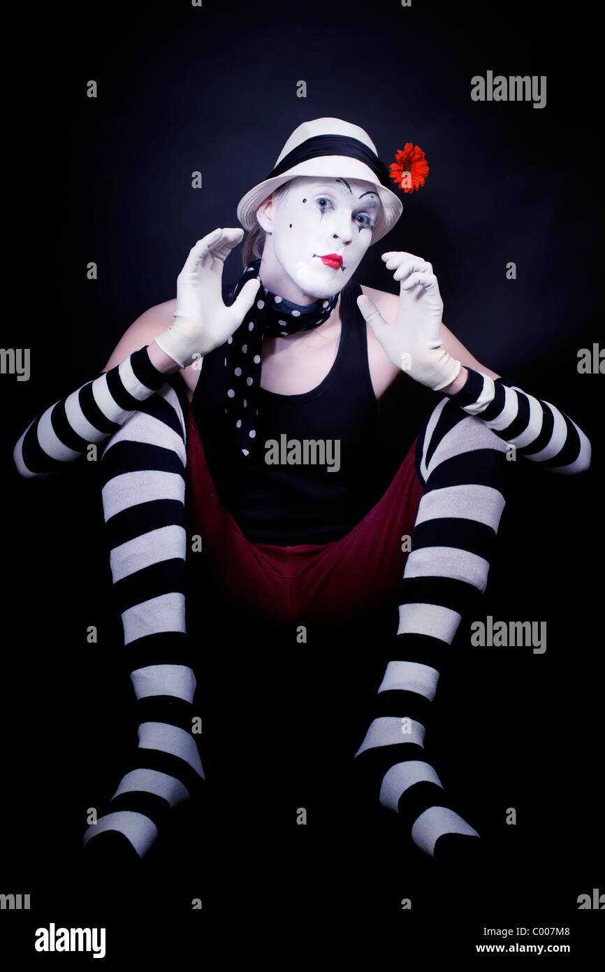 Studio portrait of Dramatic funny mime in white hat with red flower and ...