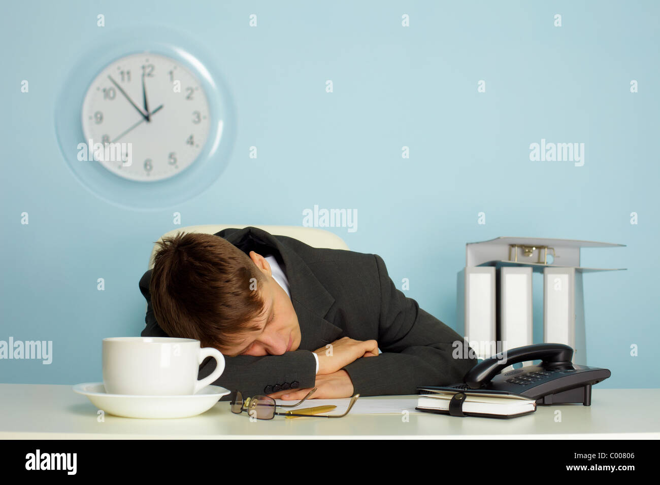 tired man sleeping on a table next to mug and phone Stock Photo - Alamy