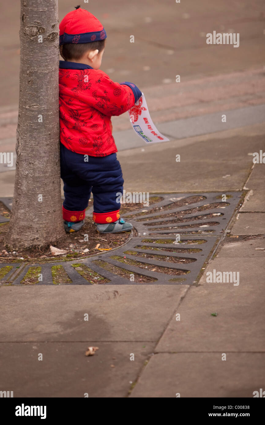 A small Chinese child wearing red and waving a lucky flag at Chinese ...