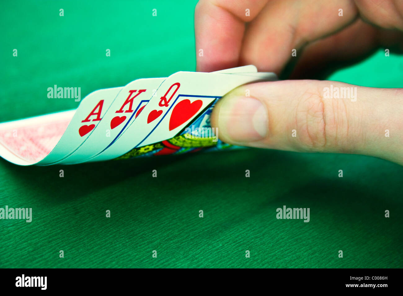 Playing cards and fingers on a green background Stock Photo - Alamy