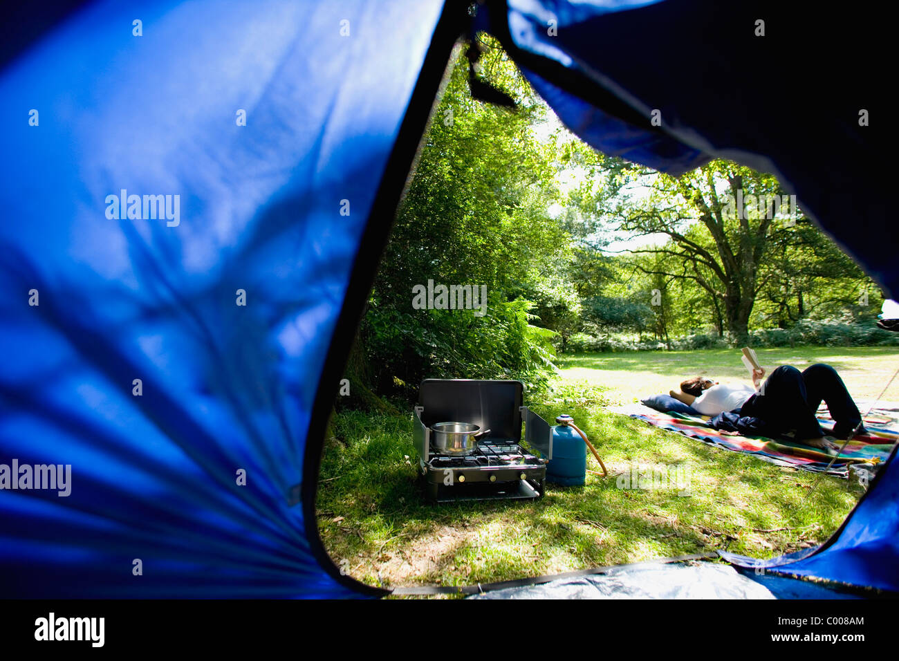 View Through Tent Of Campsite And Woman Reading Stock Photo - Alamy