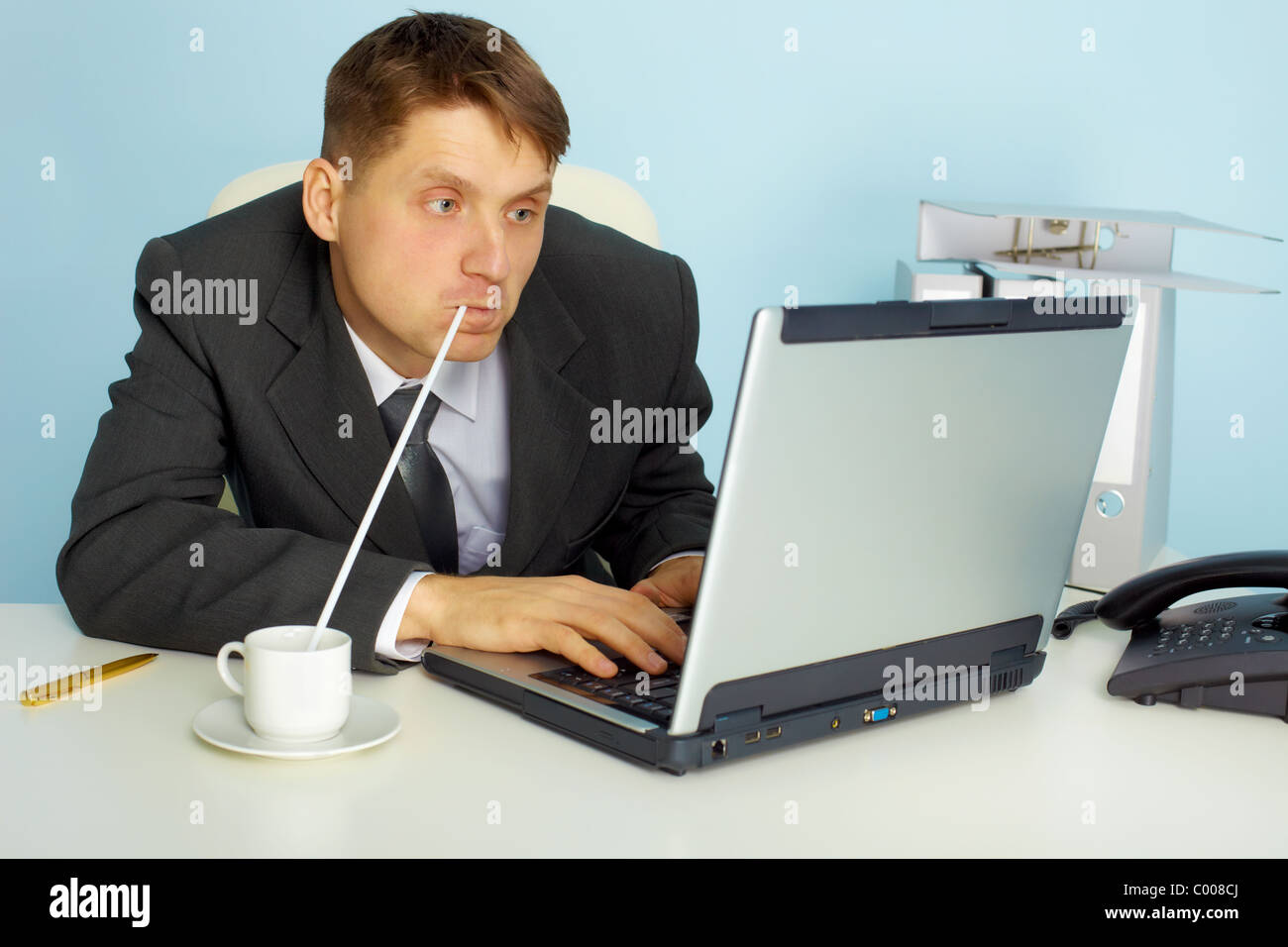 a very busy man working with laptop computer and drinks coffee through ...