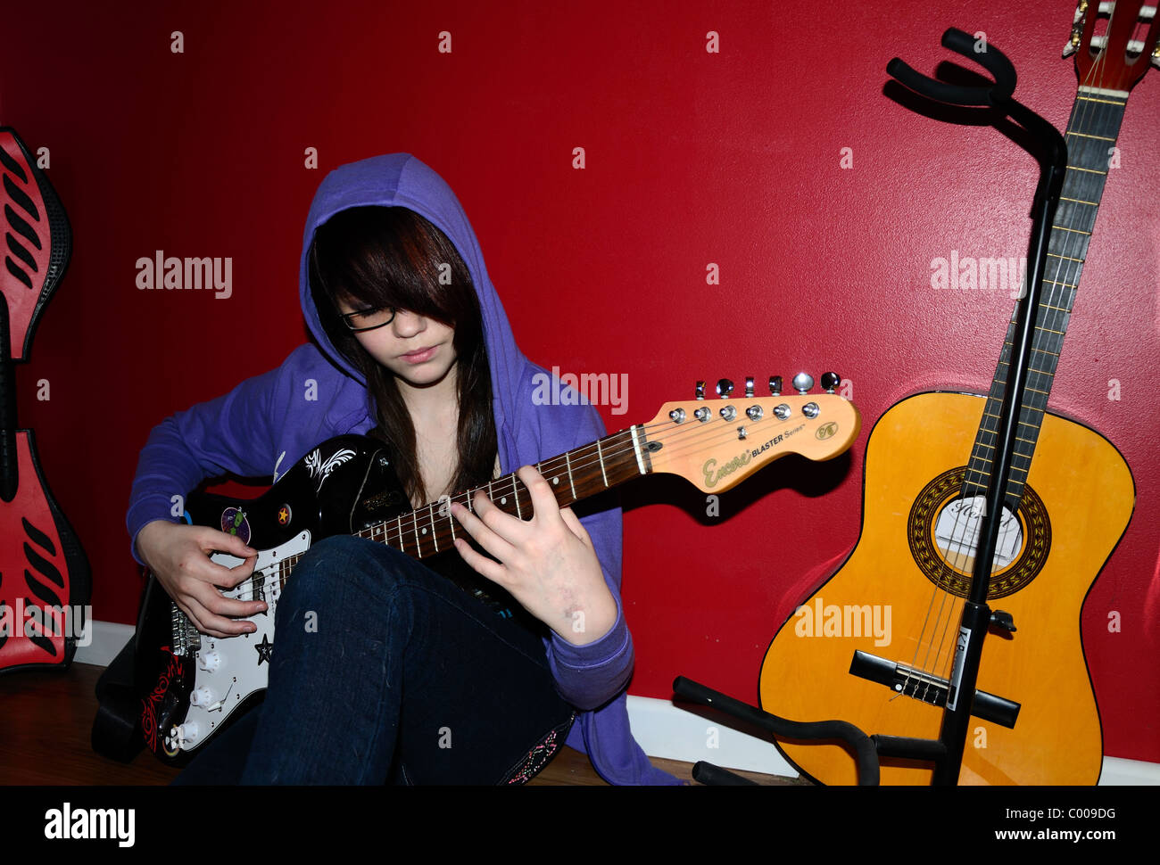 Teenage girl with rock guitar on red background Stock Photo - Alamy