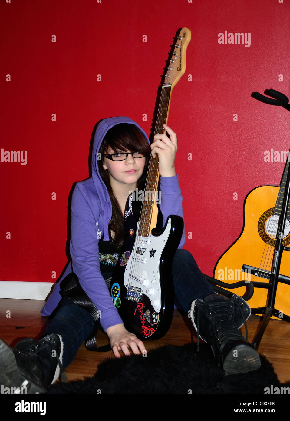 Teenage girl with rock guitar on red background Stock Photo - Alamy