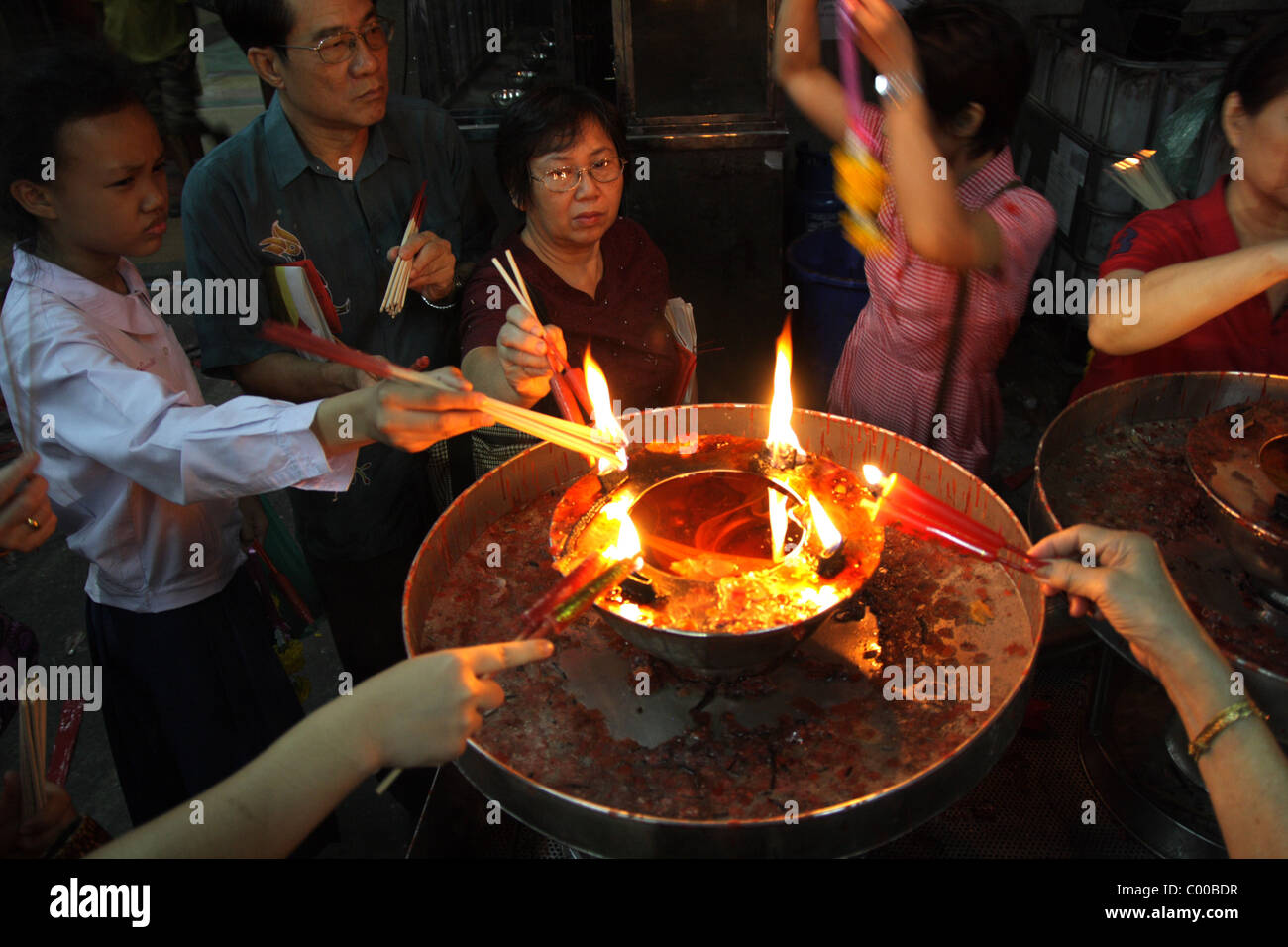 Thai people light incense sticks as people gather at a Chinese temple ...