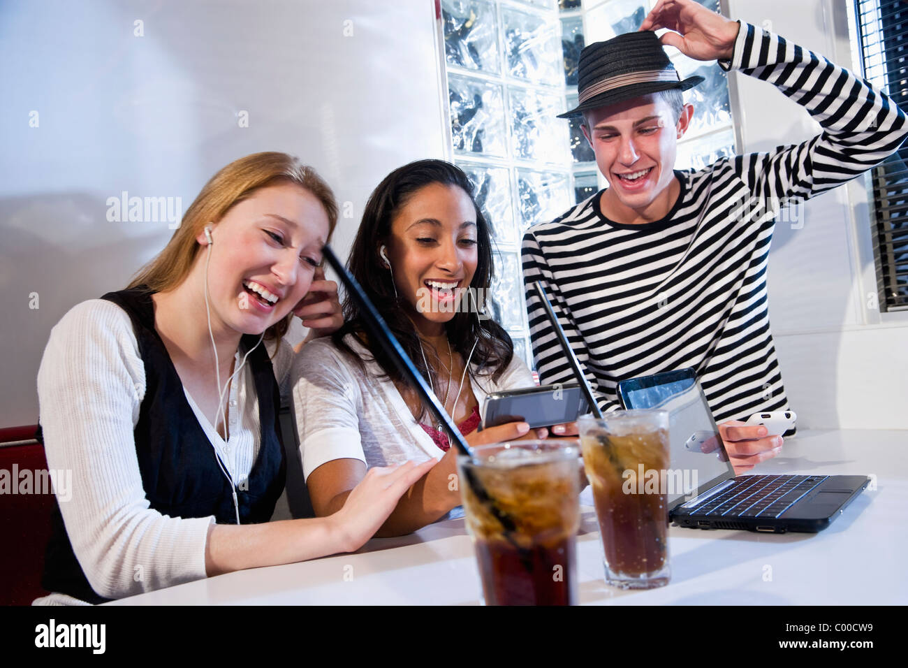 Teenage friends using technology in diner Stock Photo - Alamy