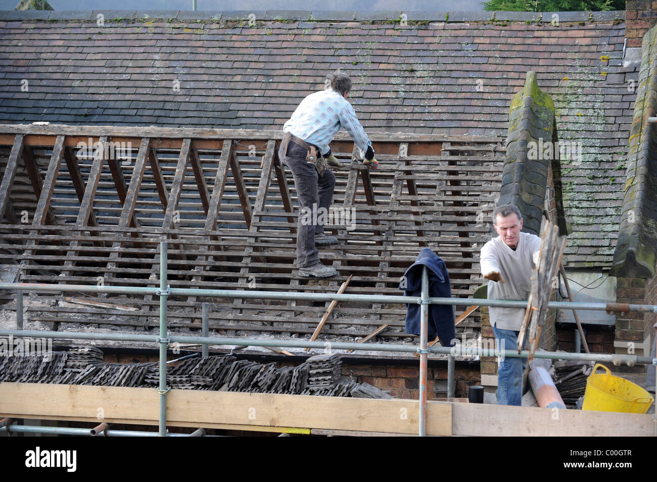 Builders repairing roof on old house England Uk Stock Photo - Alamy
