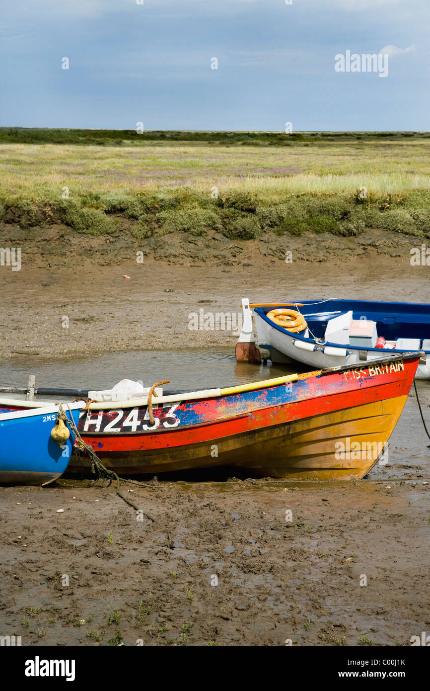 Boats in mud of small estuary by marshes Stock Photo - Alamy