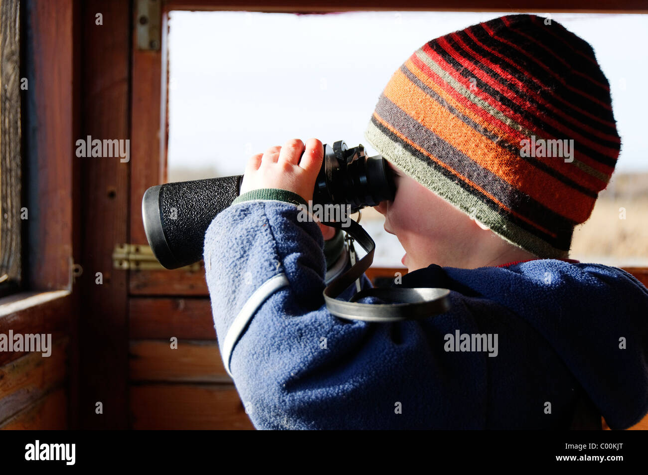 A young boy looking through binoculars from a bird hide at RSPB Conwy ...