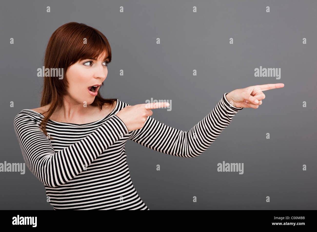 Young woman looking and pointing to her left side Stock Photo - Alamy