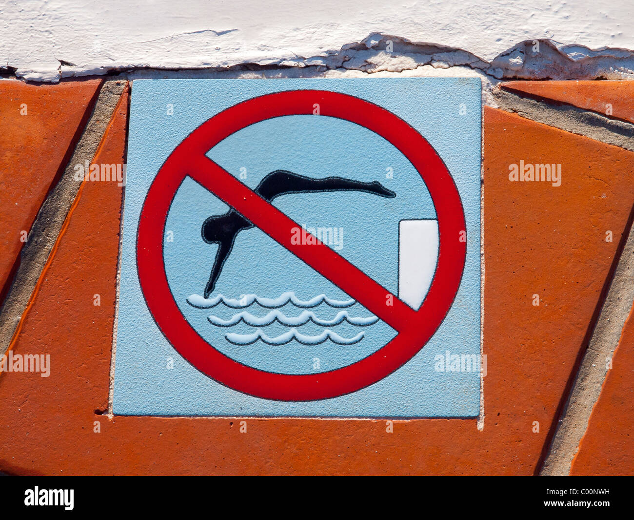A ceramic tile warning sign against diving into shallow water in a ...