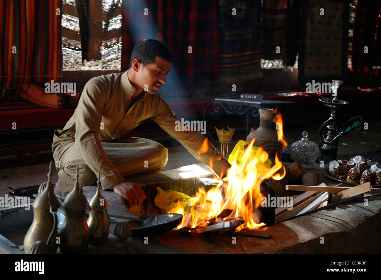 Man setting fire to make tea at a bedouin tent next to Qasr Kharana ...