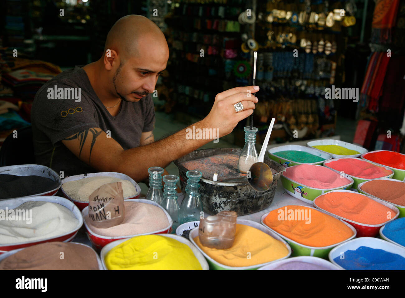 An artist filling souvenir bottles with desert sand, Amman, Jordan ...