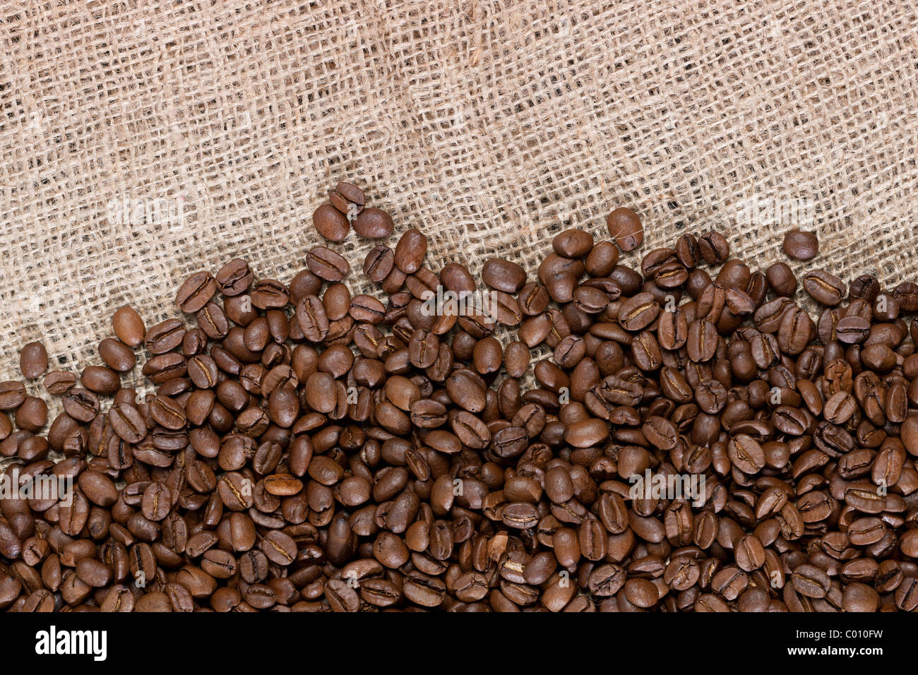 Background image of many coffee beans spilled out on a canvas material ...