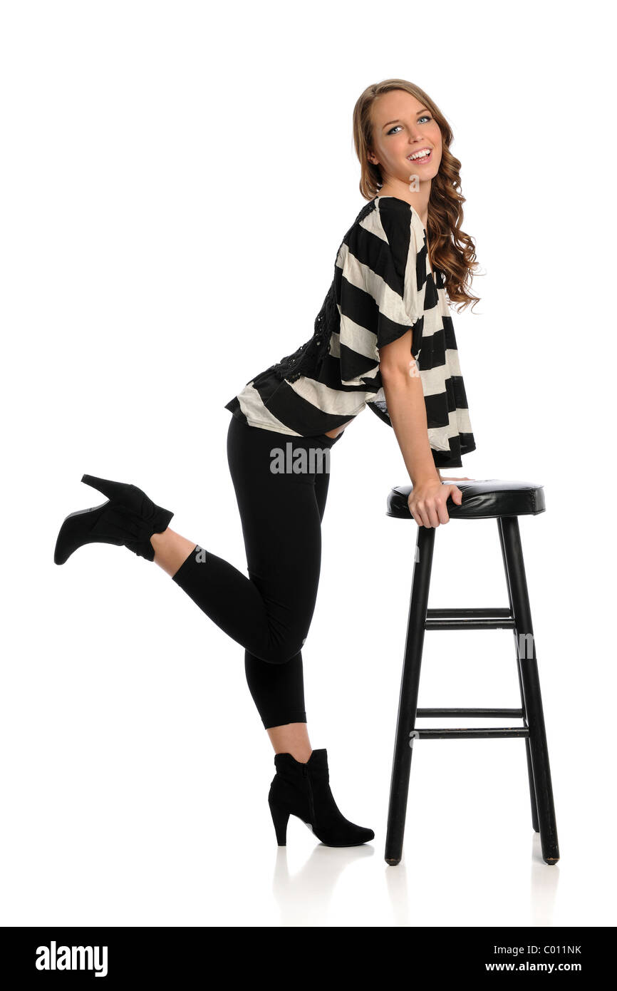 Portrait of beautiful young woman leaning on stool isolated over white ...