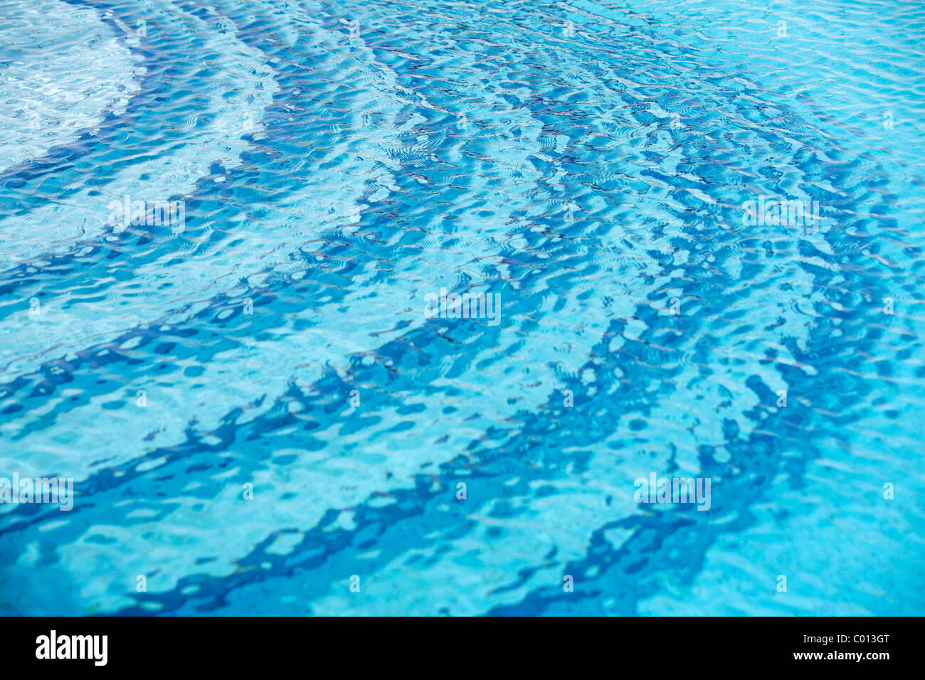 Rippled water surface in a swimming pool, detail, blue with steps below ...